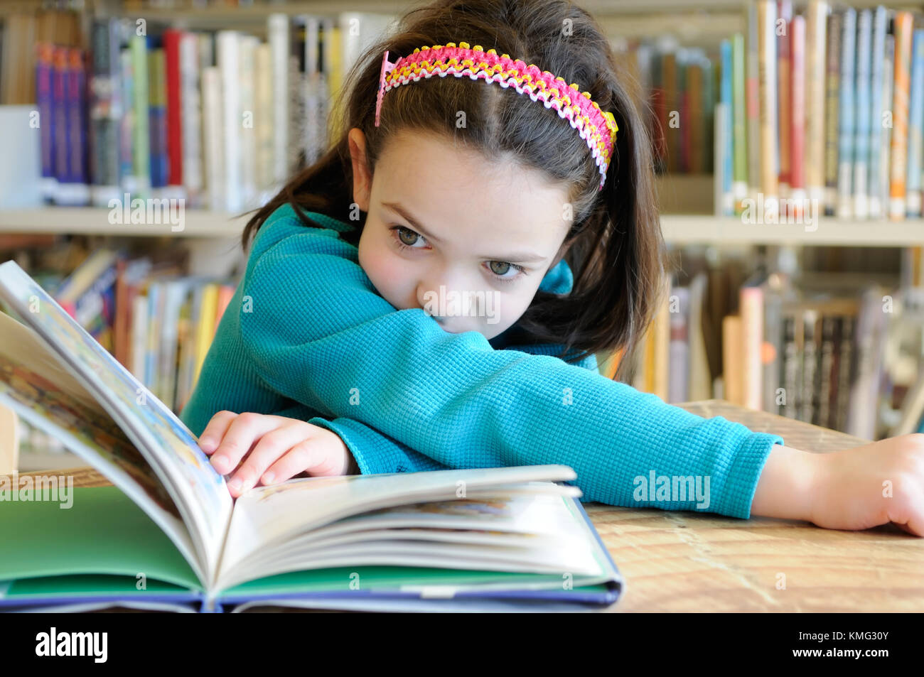 Young girl reading book in the library Stock Photo - Alamy