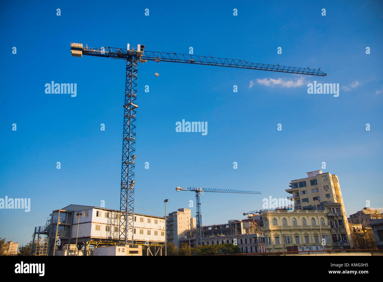 Construction cranes rise over typical colonial architecture against ...