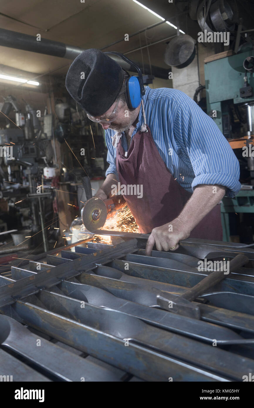 Blacksmith cutting iron bar with angle grinder at workshop Stock Photo ...