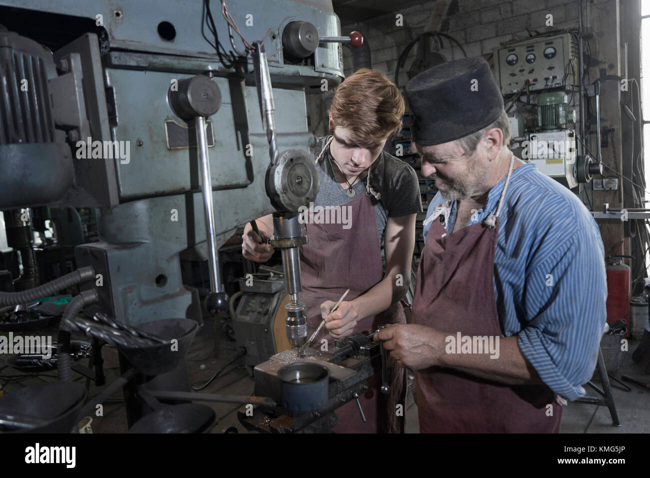 Blacksmith explaining apprentice handling of drilling machine Stock ...