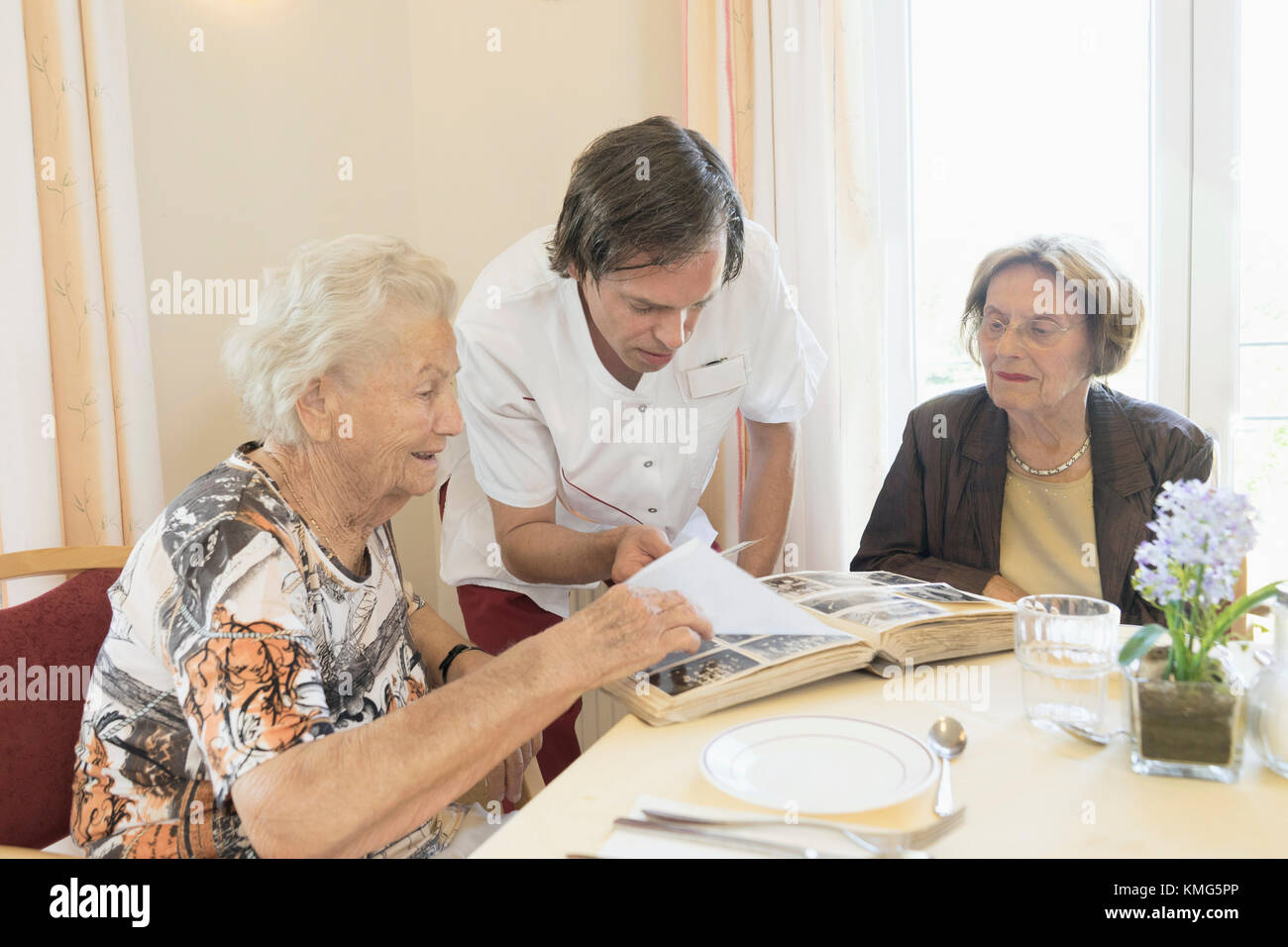 Caretaker watching photo album with senior woman at rest home Stock ...