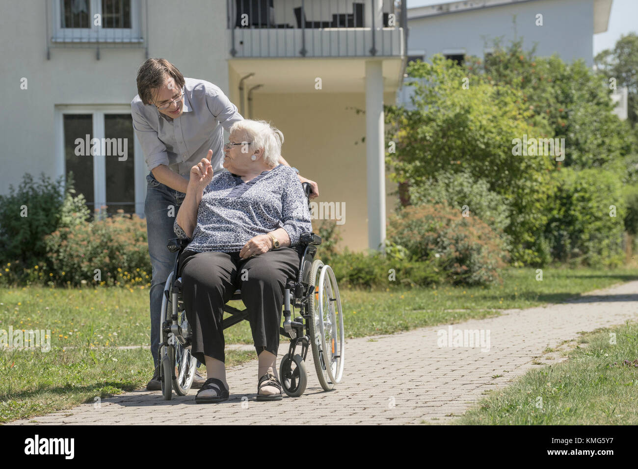 Son walking with disabled mother on wheelchair Stock Photo - Alamy
