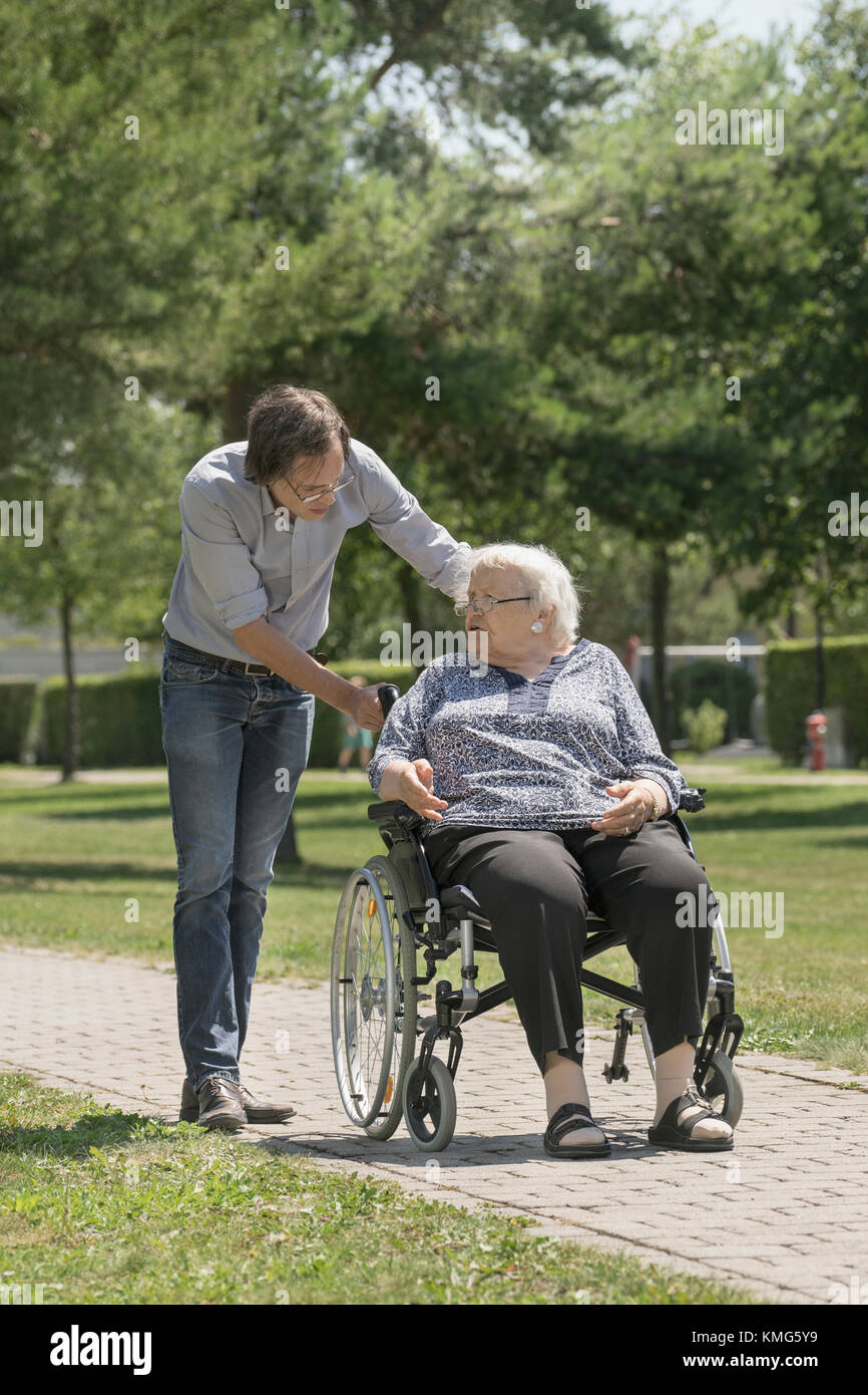 Son walking with disabled mother on wheelchair Stock Photo - Alamy