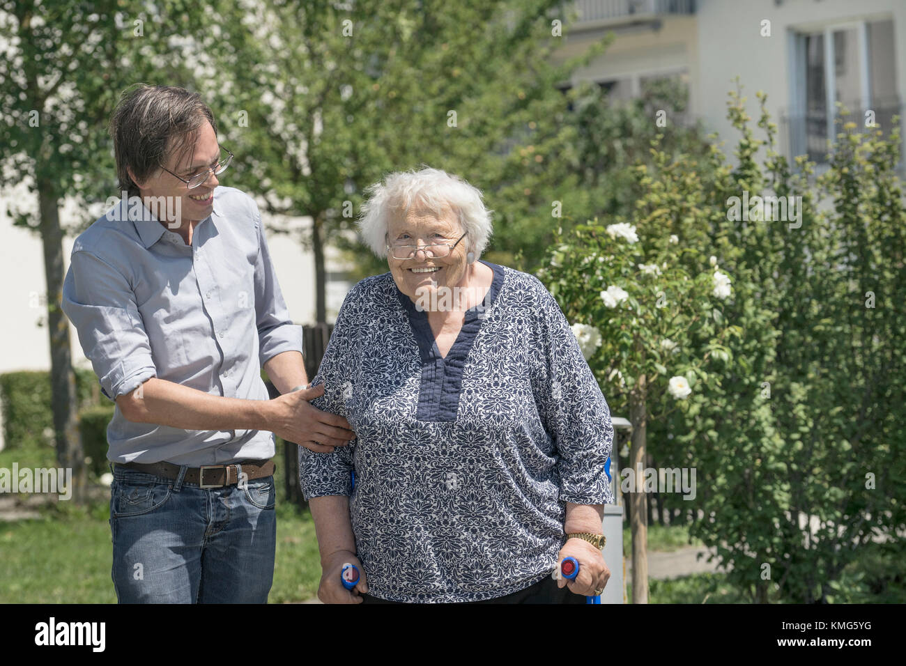 Son walking with disabled mother on crutches Stock Photo - Alamy