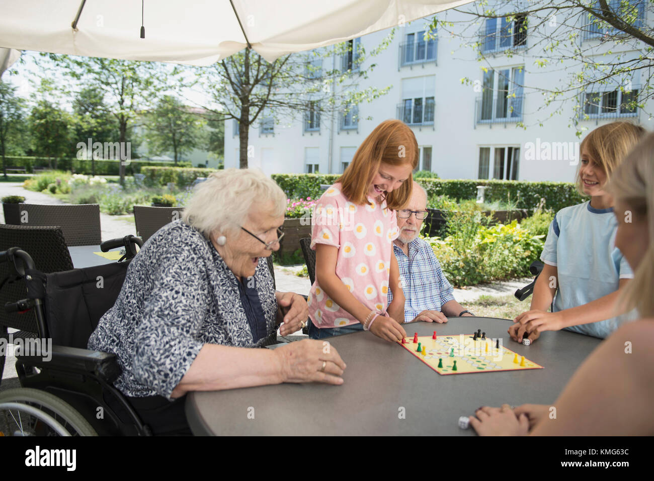 Multi-generation family playing board game at nursing home Stock Photo ...