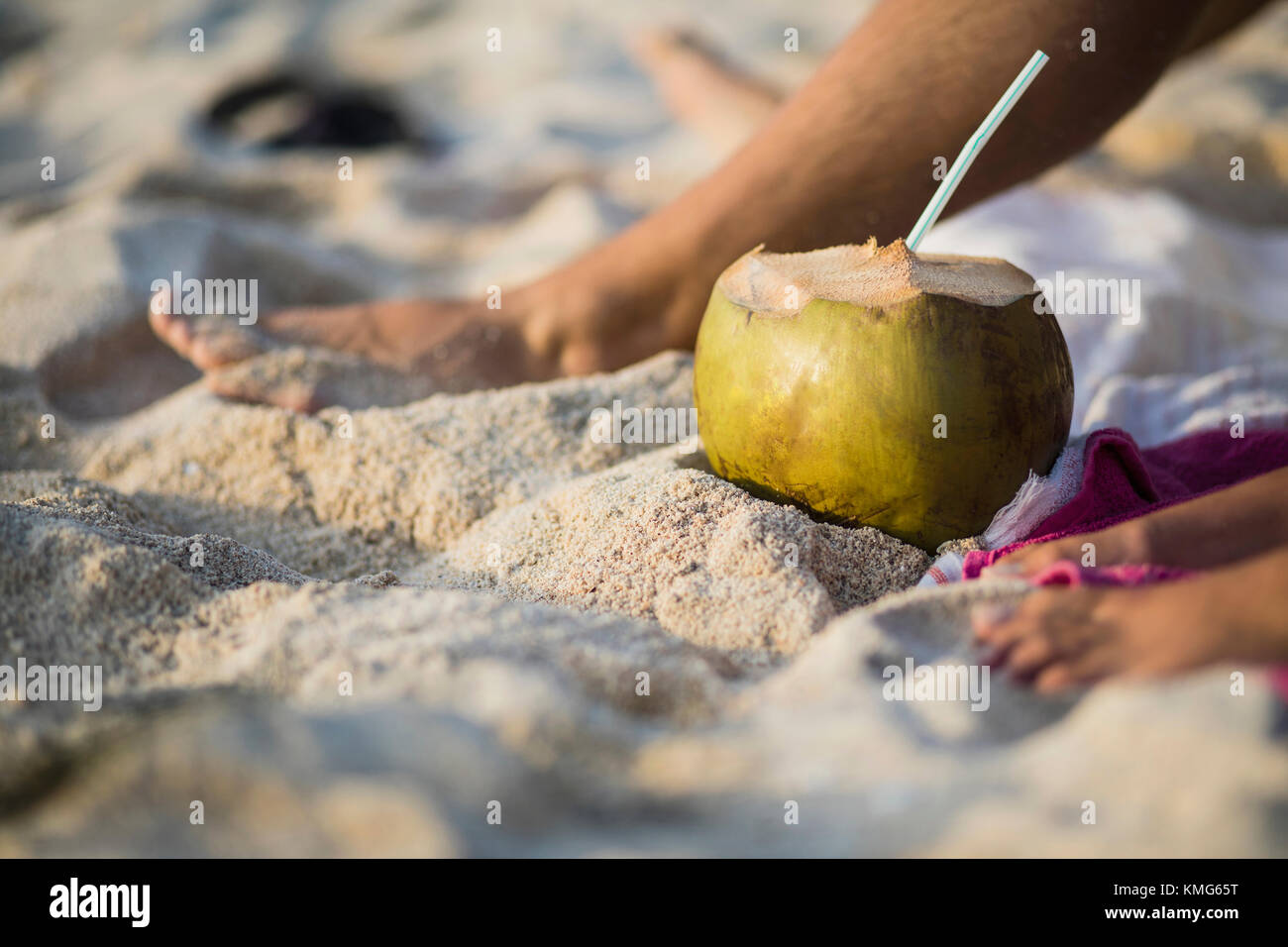 Coconut between legs on sand Stock Photo - Alamy