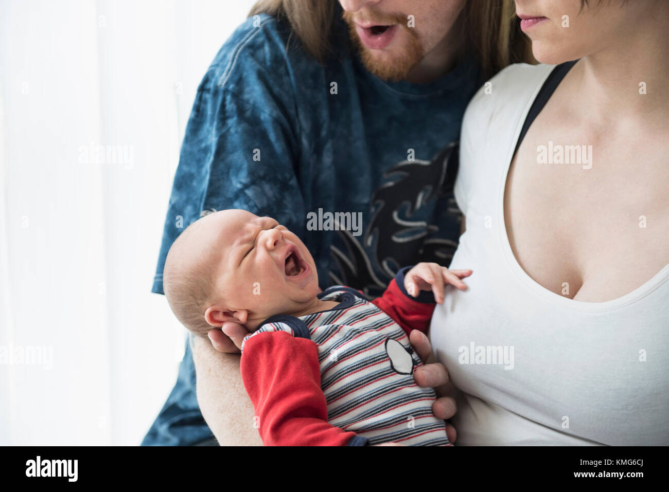 Parents holding crying baby boy in their arms Stock Photo - Alamy
