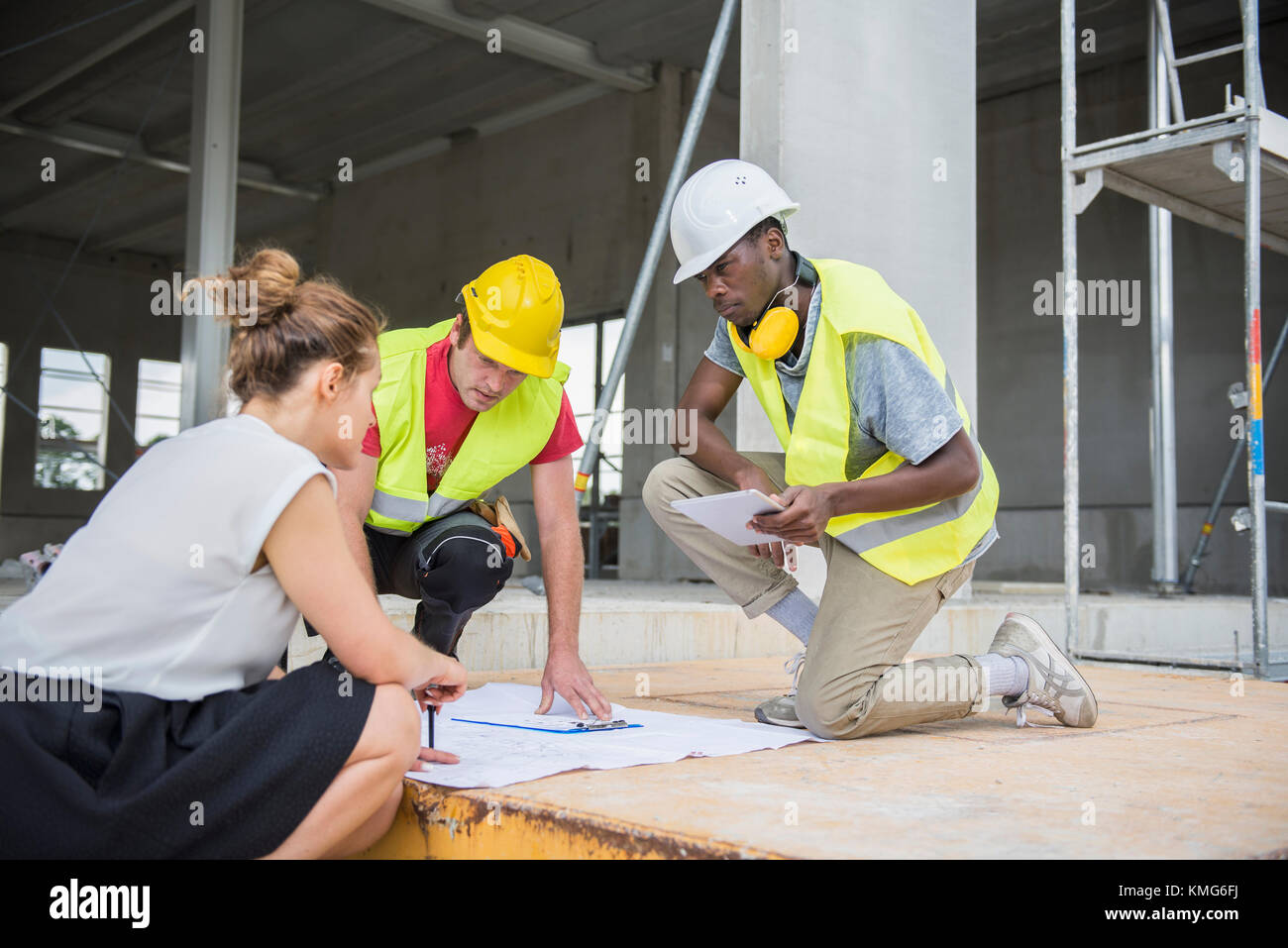 Architect discussing blueprint with construction workers at building ...