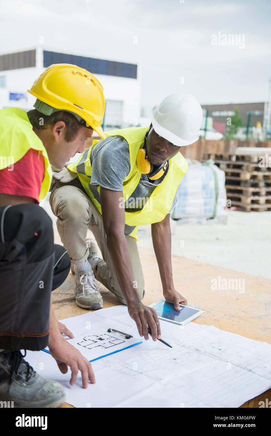Construction workers reviewing blueprint at construction site Stock ...