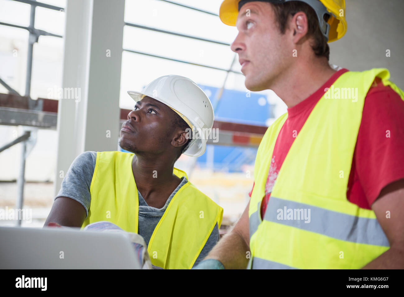 Construction workers looking up at building site Stock Photo - Alamy