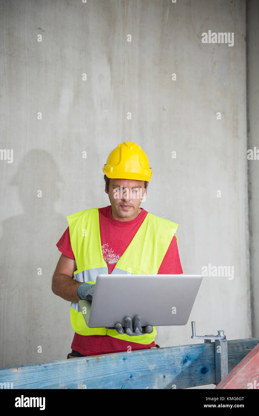 Construction worker using laptop at building site Stock Photo - Alamy