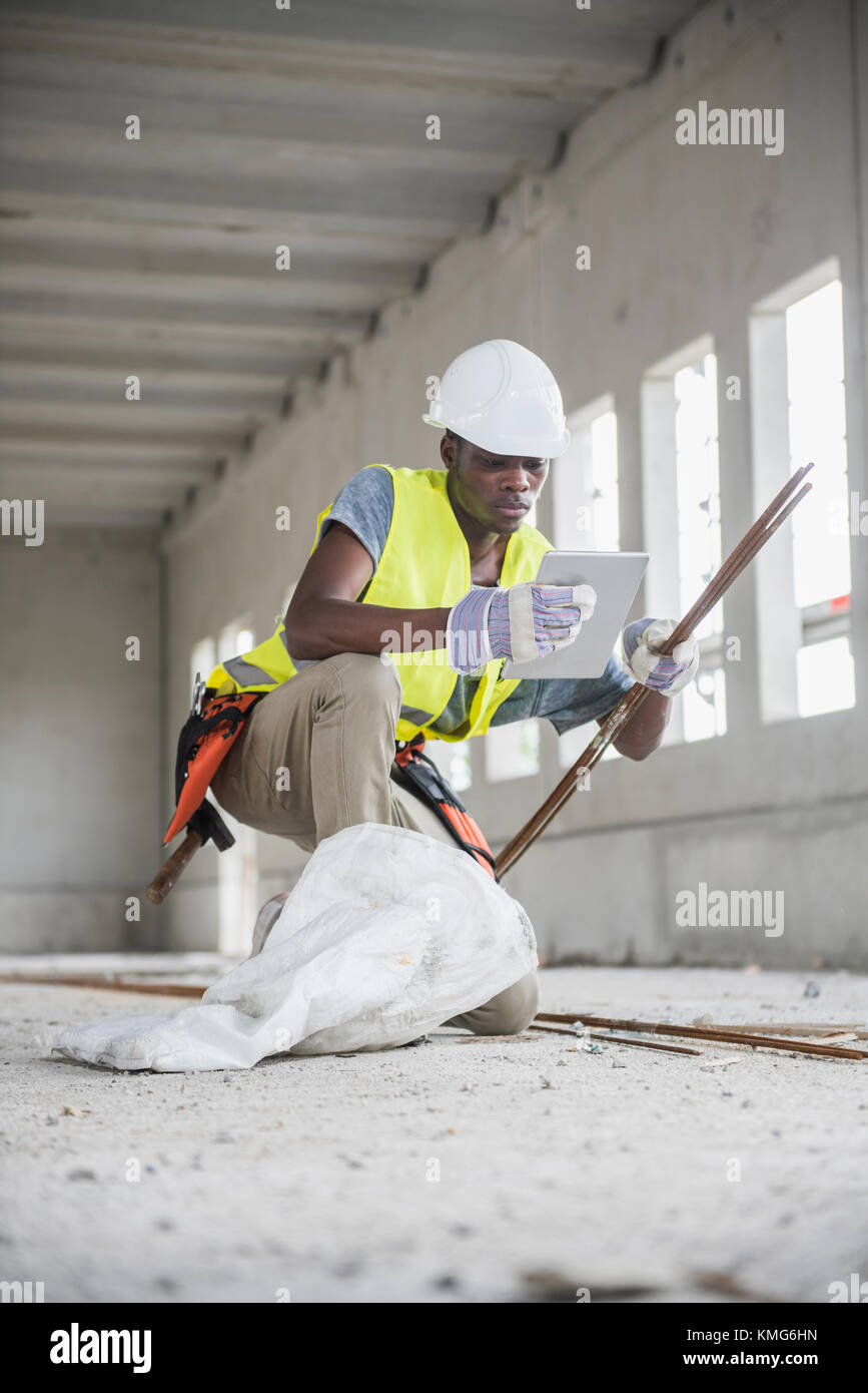 Construction worker holding digital tablet and iron bars at building ...
