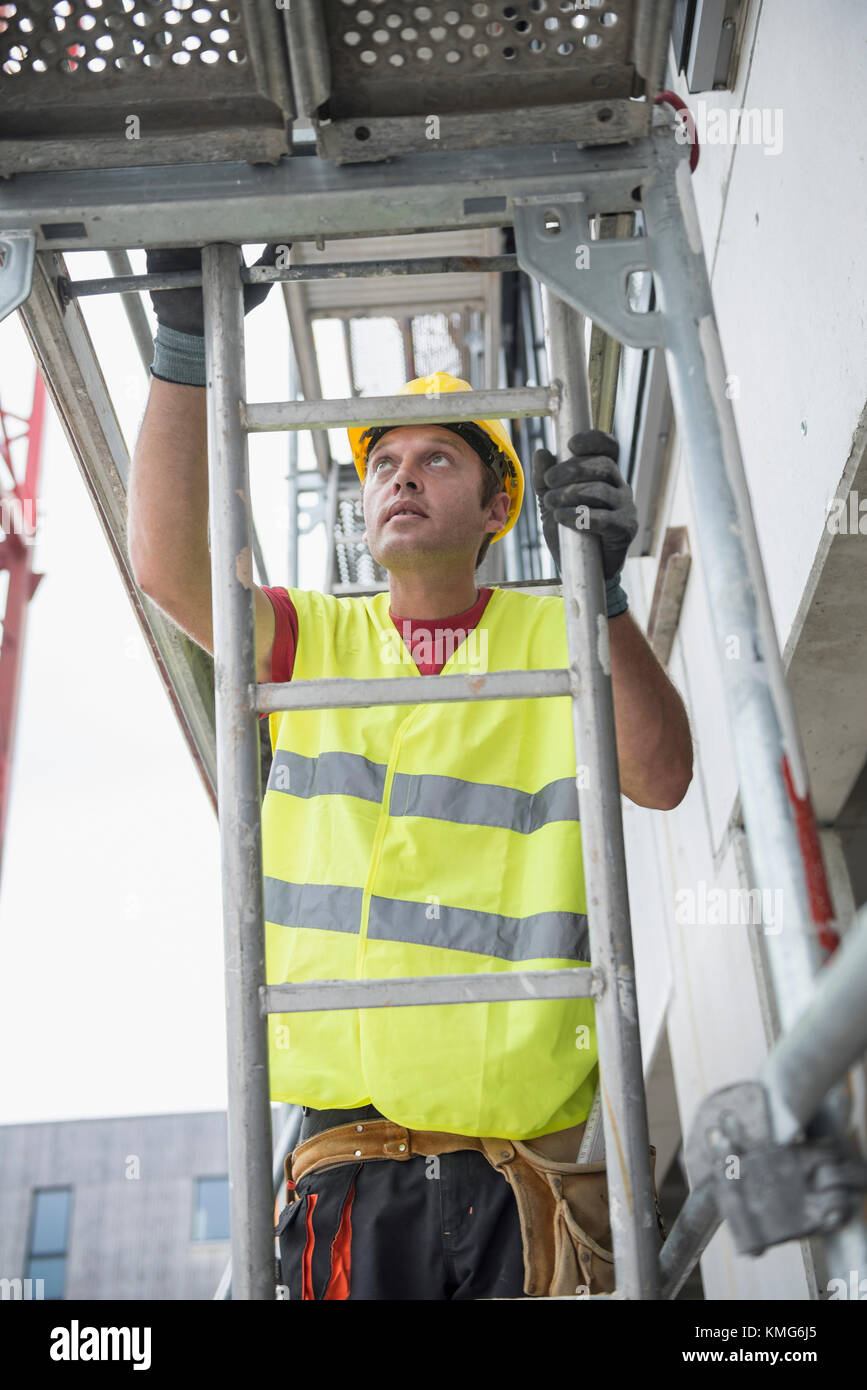 Construction worker at building site climbing up a ladder Stock Photo ...