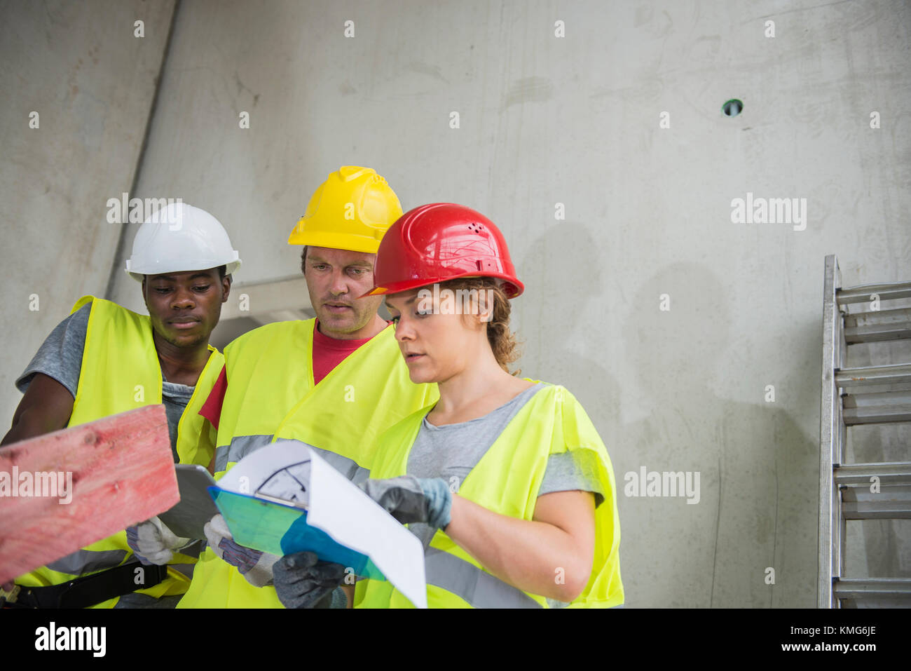 Construction workers with architectural plan at building site Stock ...