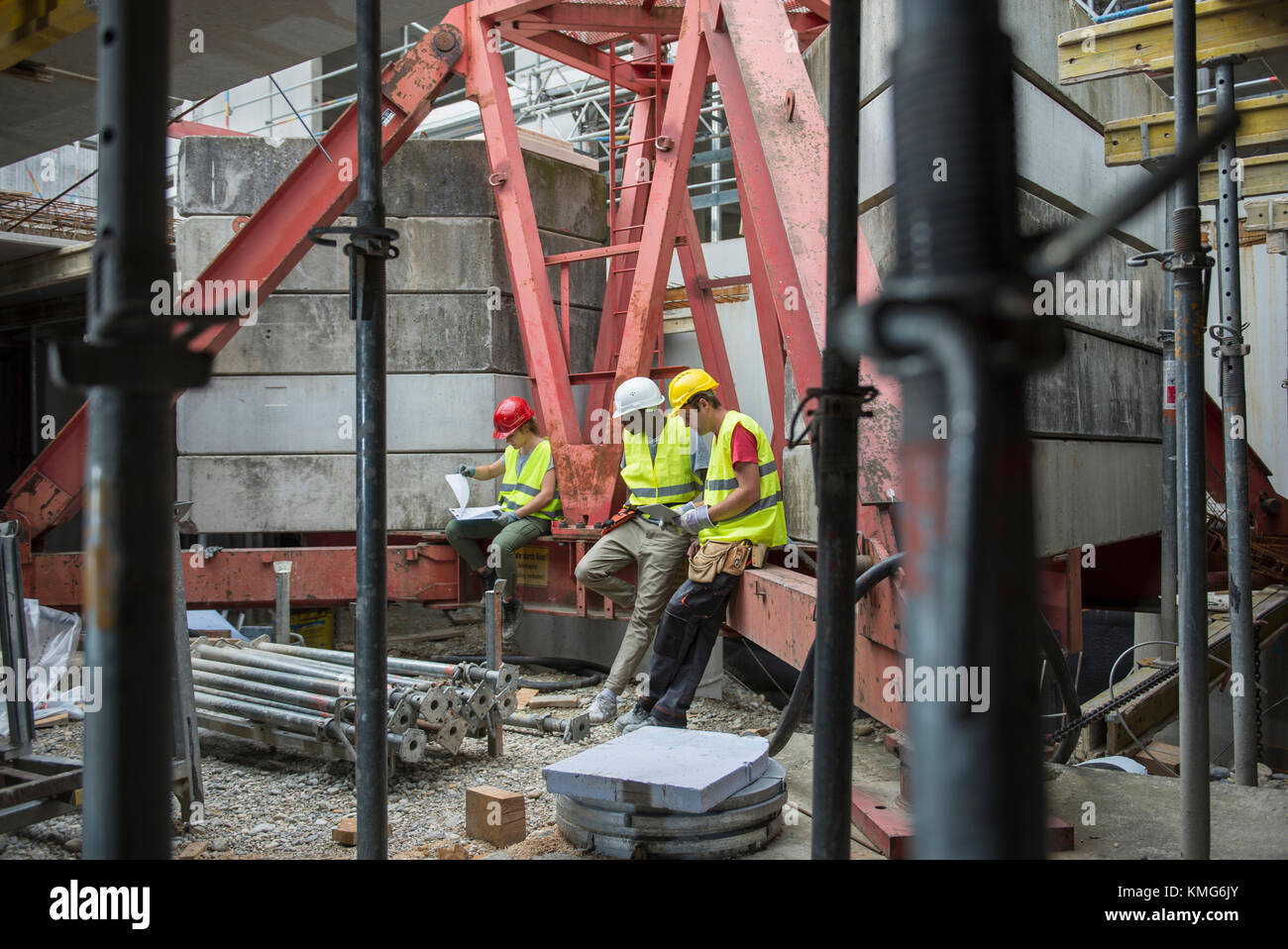 Construction workers with architectural plan and digital table at ...