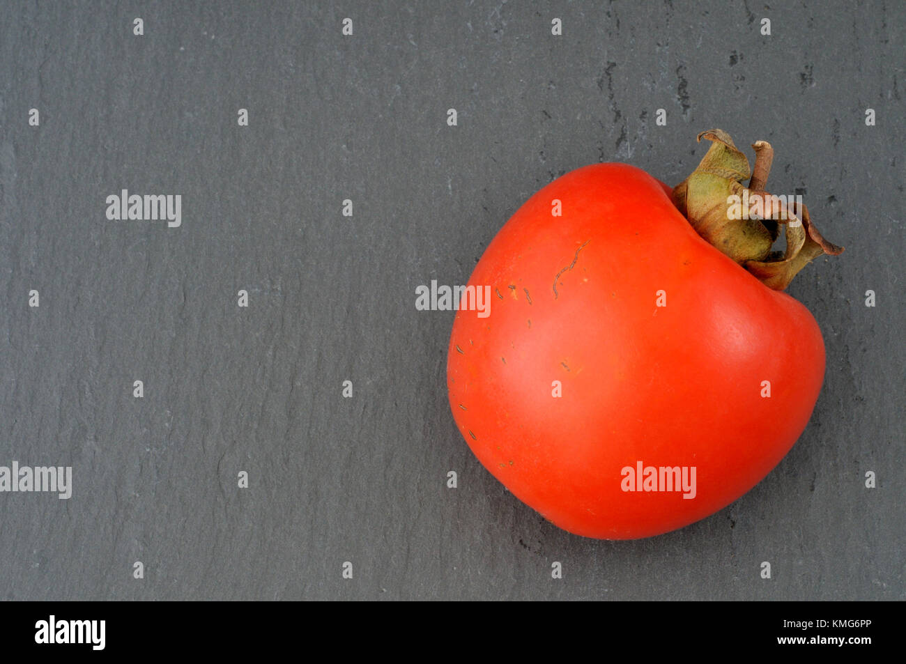 persimmon on slate plate, flat Stock Photo - Alamy