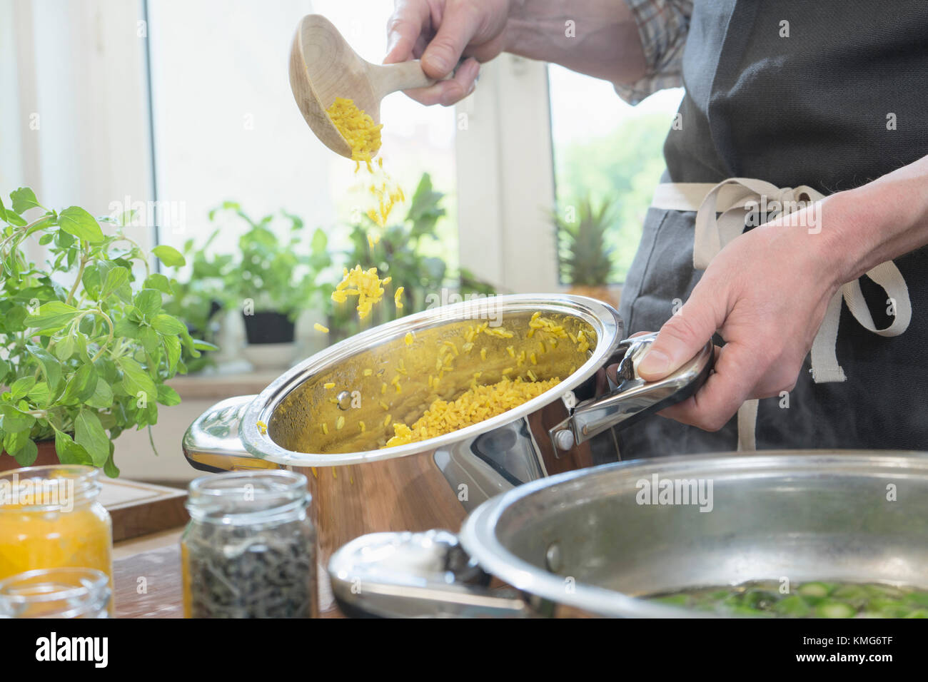 Man stirring rice with wooden spoon in pot Stock Photo - Alamy
