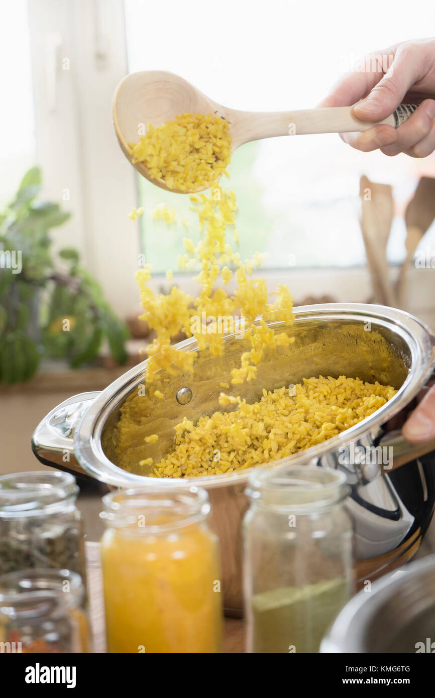 Man stirring rice with wooden spoon in pot Stock Photo - Alamy
