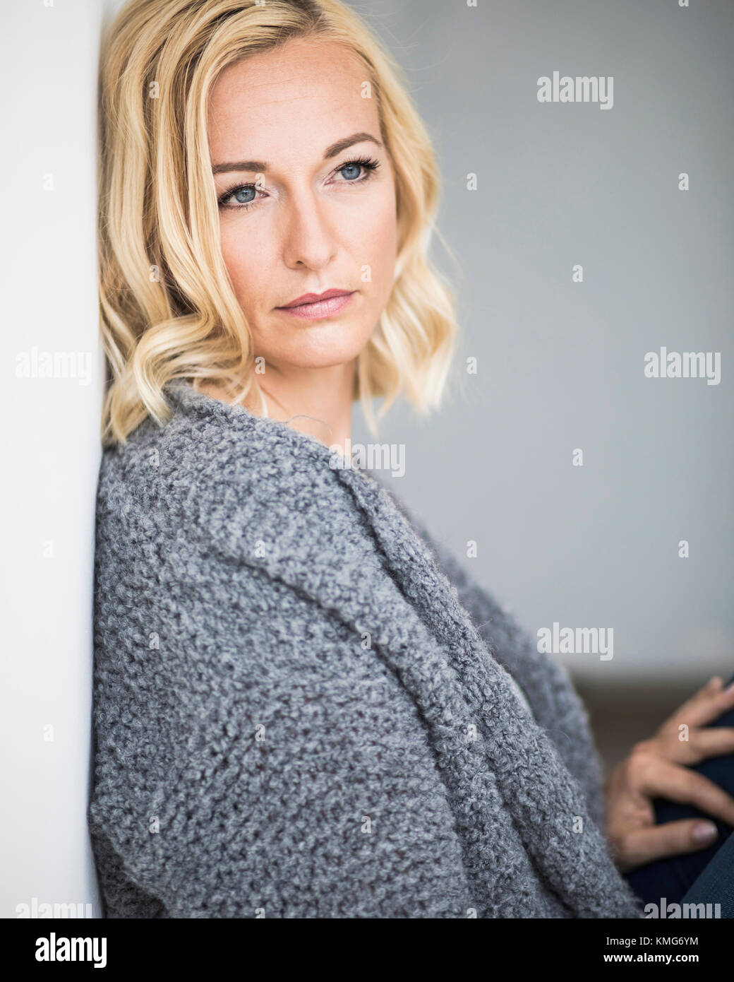 Introspective woman leaning against a wall Stock Photo - Alamy