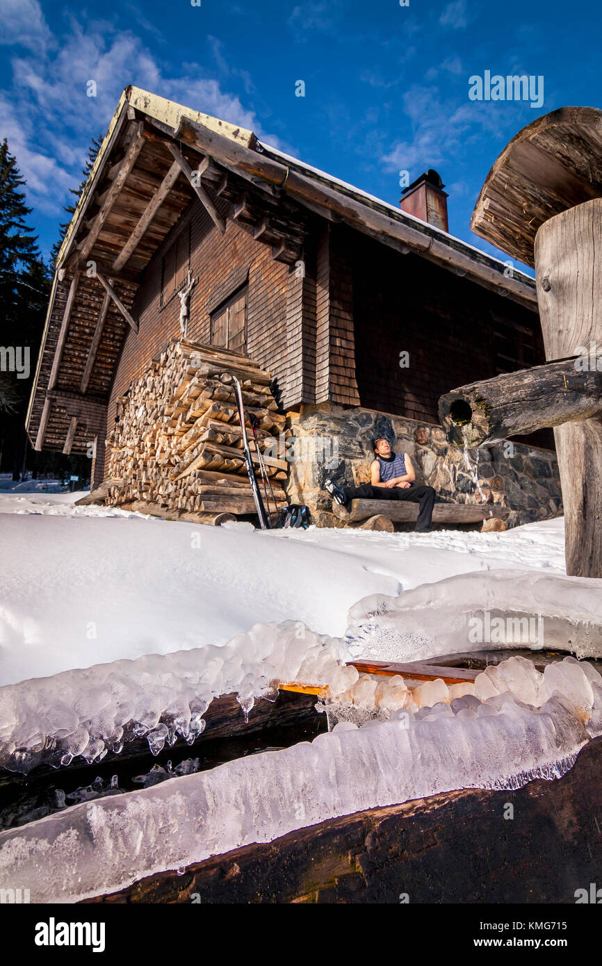 Man taking rest on bench in front of a log cabin Stock Photo - Alamy