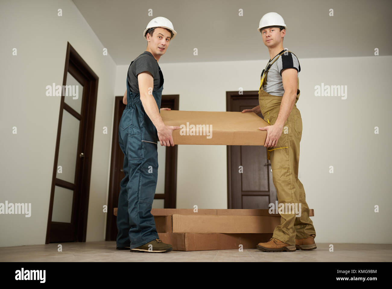 Two mans carry box. Workers delivery cardboard boxes Stock Photo - Alamy