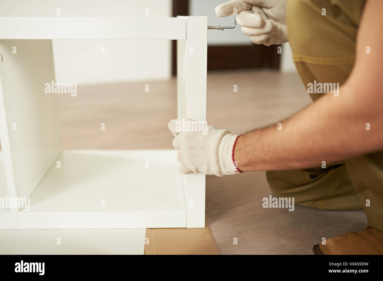 Close-up of assembling white wardrobe. Installing furniture in house ...