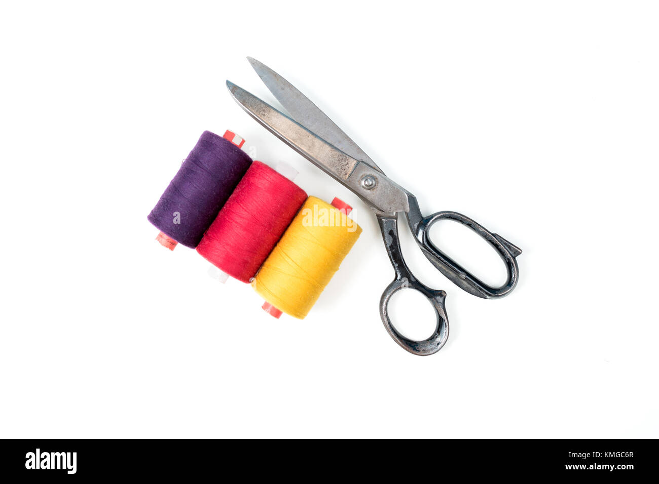 Colored sewing thread coils with old metal scissors on white background ...
