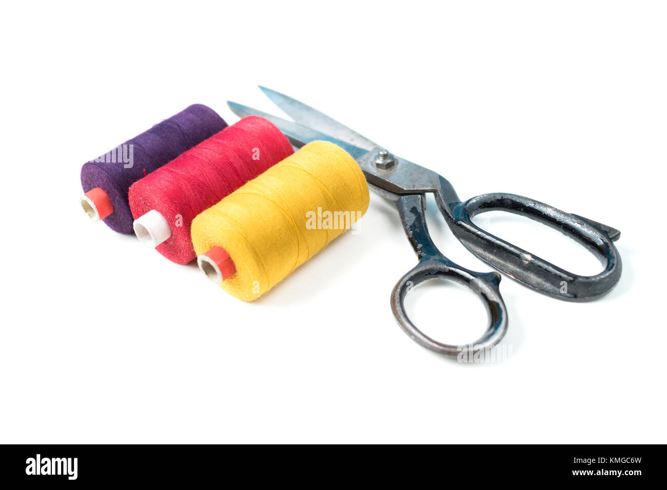 Colored sewing thread coils with old metal scissors on white background ...
