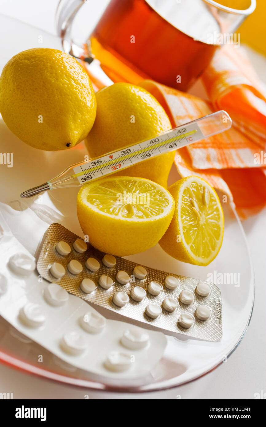 black tea with fresh lemons and flu pills in blister with thermometer ...