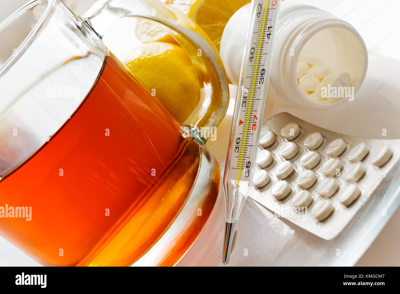 black tea with fresh lemons and flu pills in blister with thermometer ...