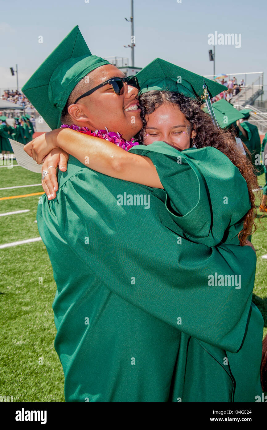 In traditional graduation caps and gowns, two Hispanic high school ...