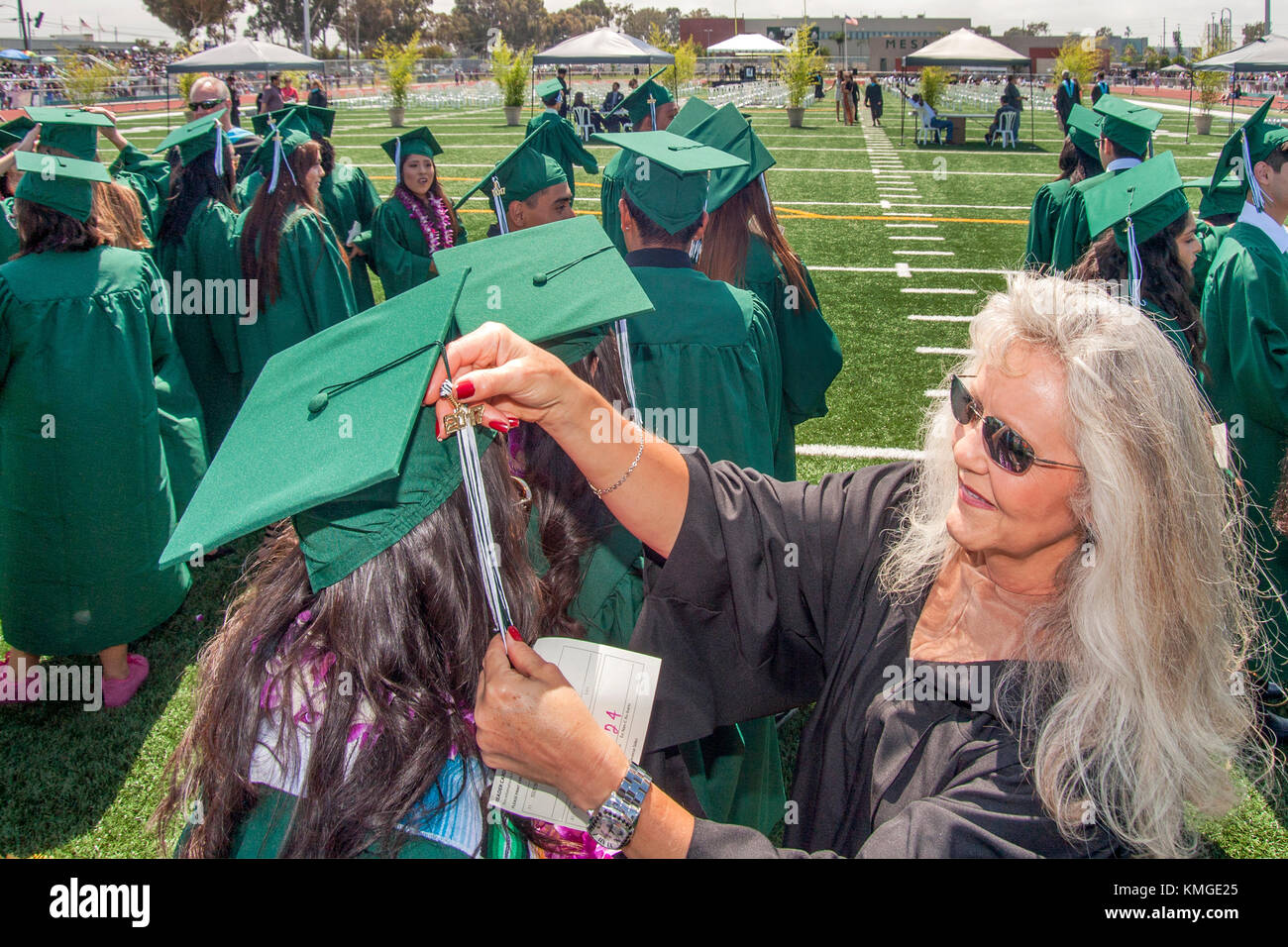 A high school teacher adjusts student's graduation cap tassels at ...