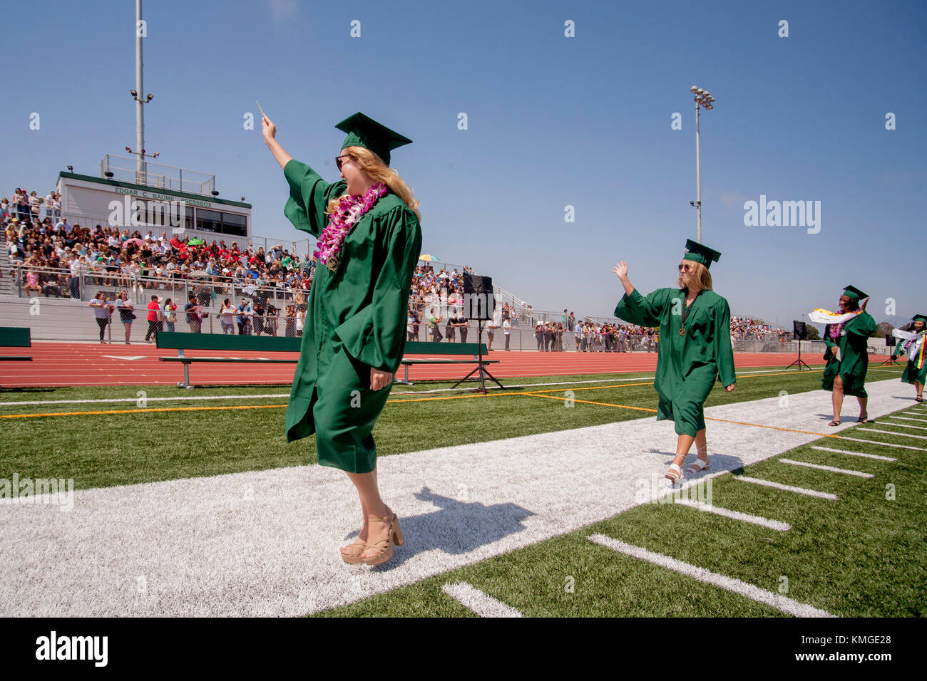 A procession of high school graduates in traditional caps and gowns ...