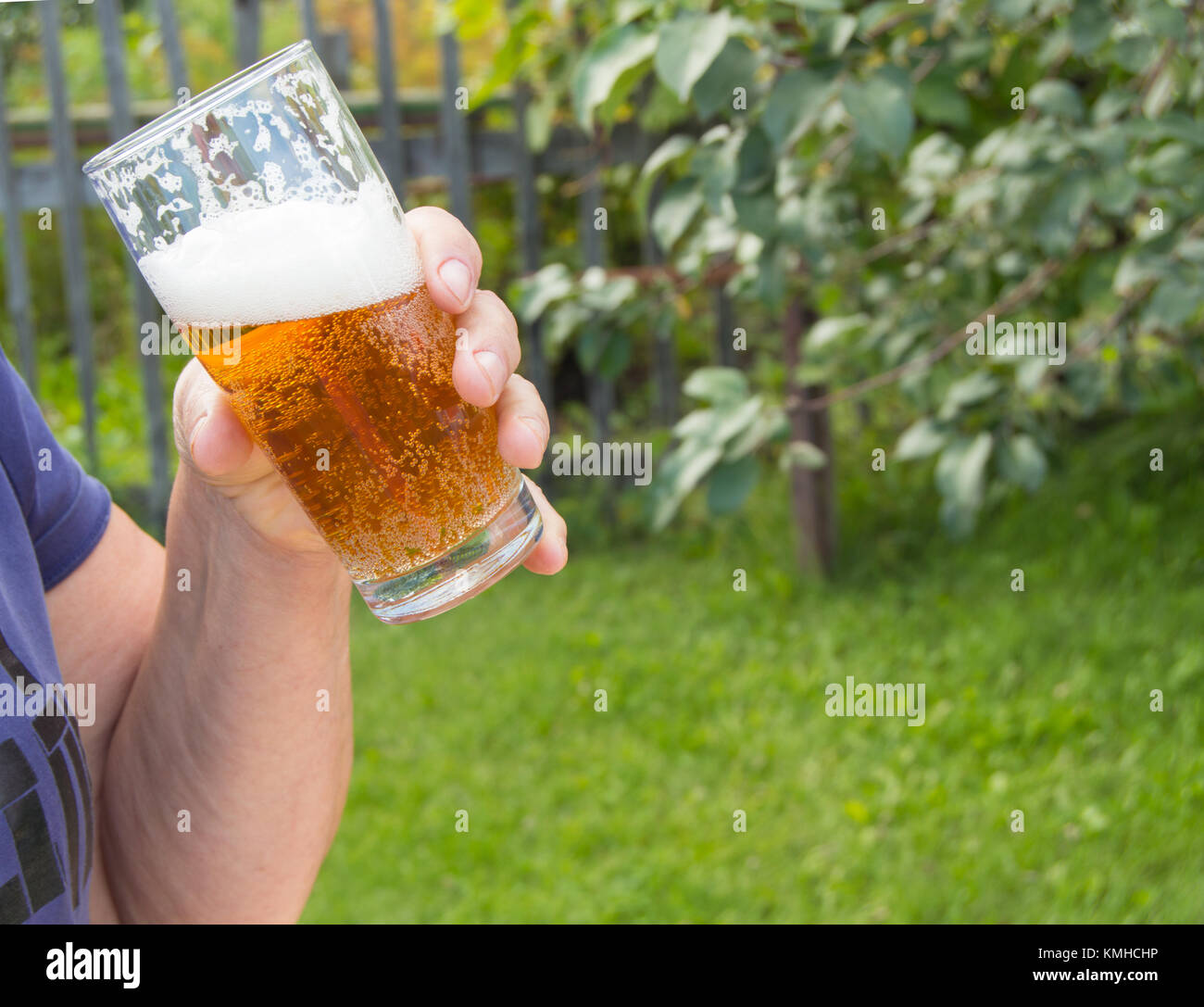 Woman's hand holding a beer with foam in glass on the background of ...
