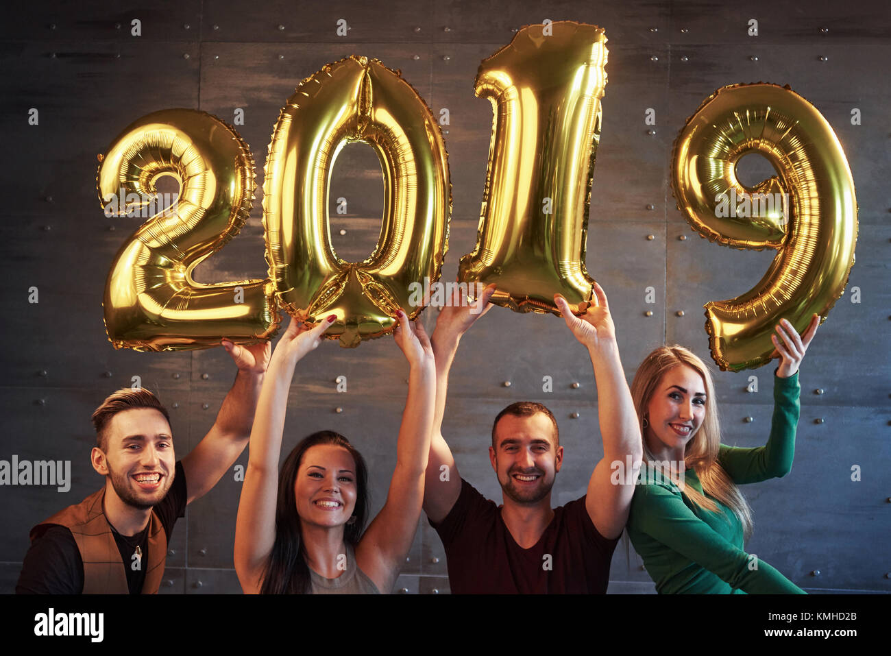 A group of merry young people hold numbers indicating the arrival of a ...