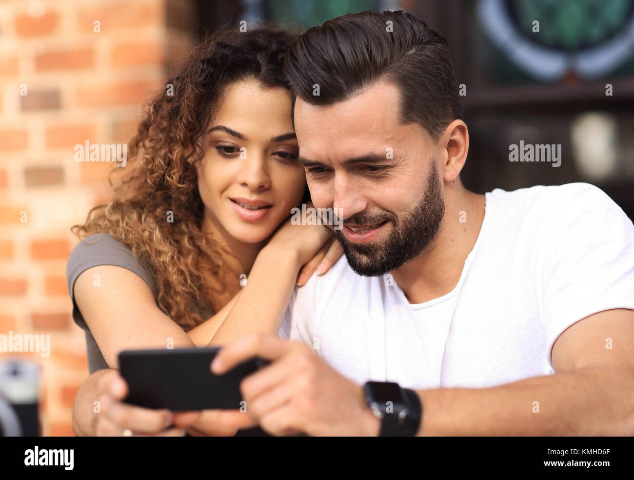 Happy couple using a smartphone sitting in terrace Stock Photo - Alamy