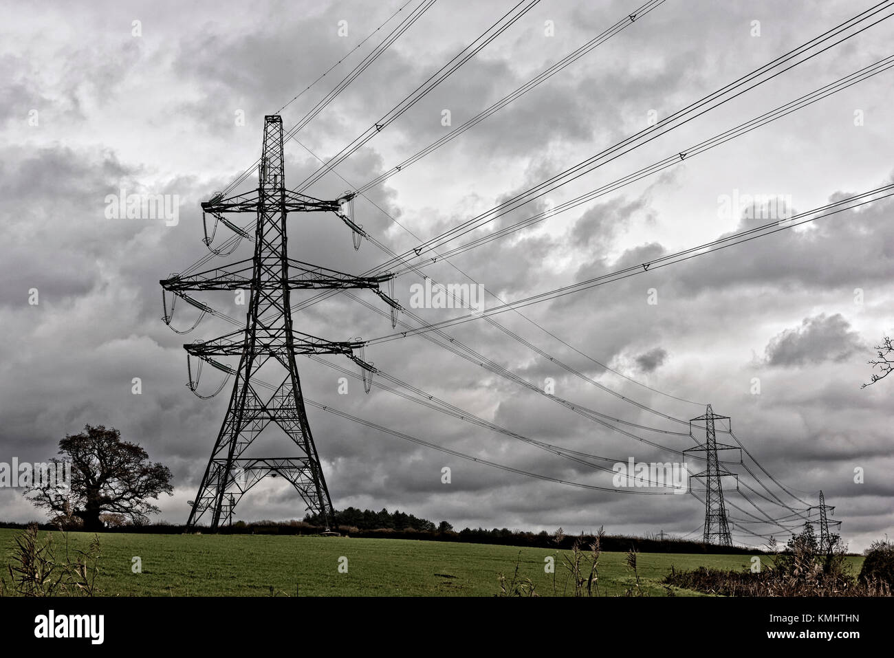 Overhead electricity cables and large pylons across open countryside ...