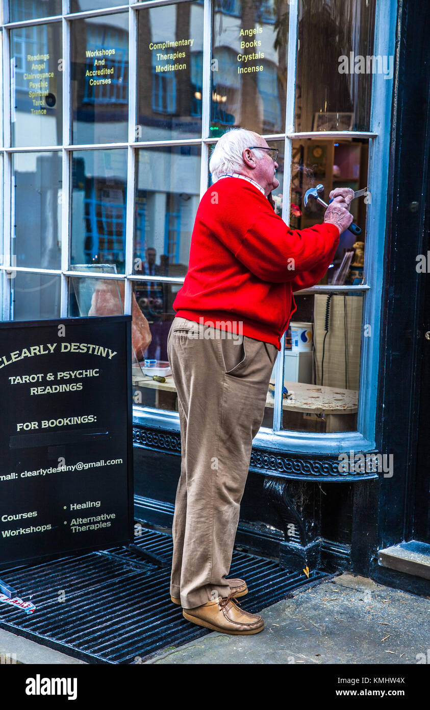 Senior man fixing a shop window, London, England, UK Stock Photo - Alamy
