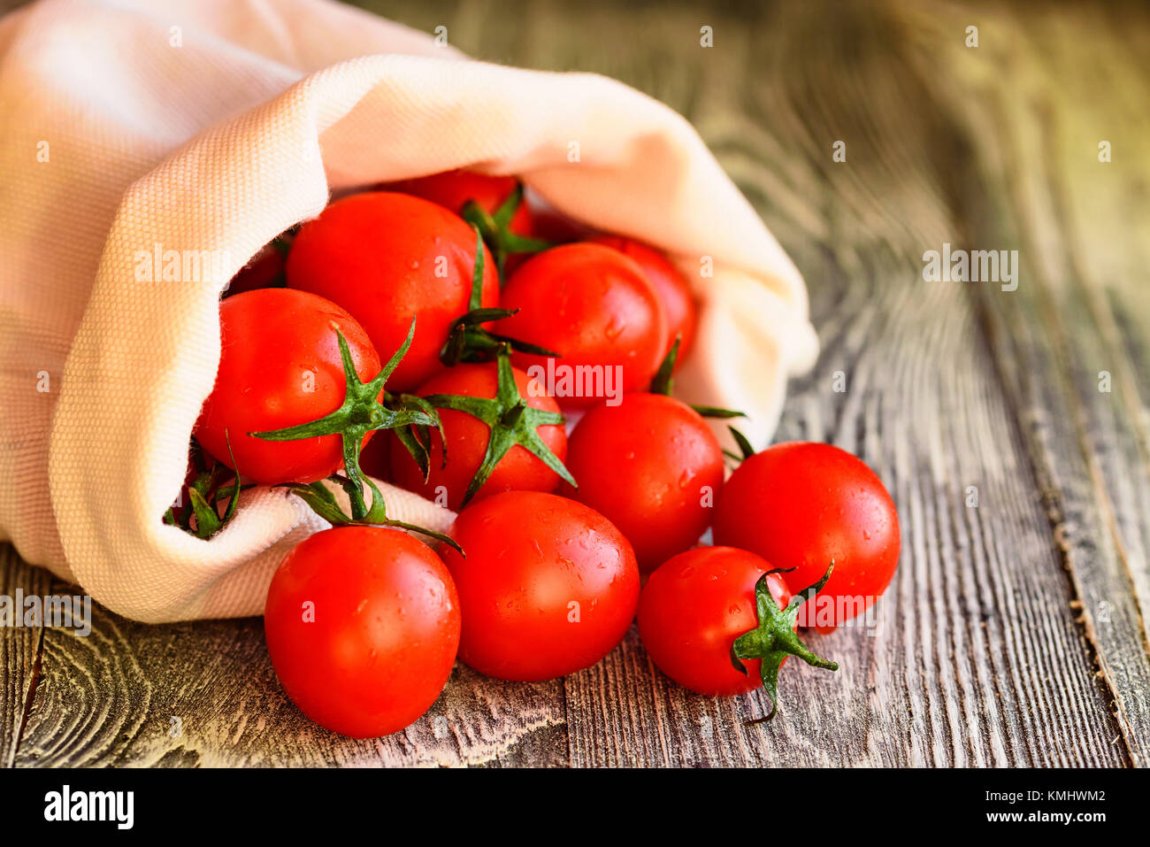 Red ripe tomatoes spill out of sack. Rustic view Stock Photo - Alamy