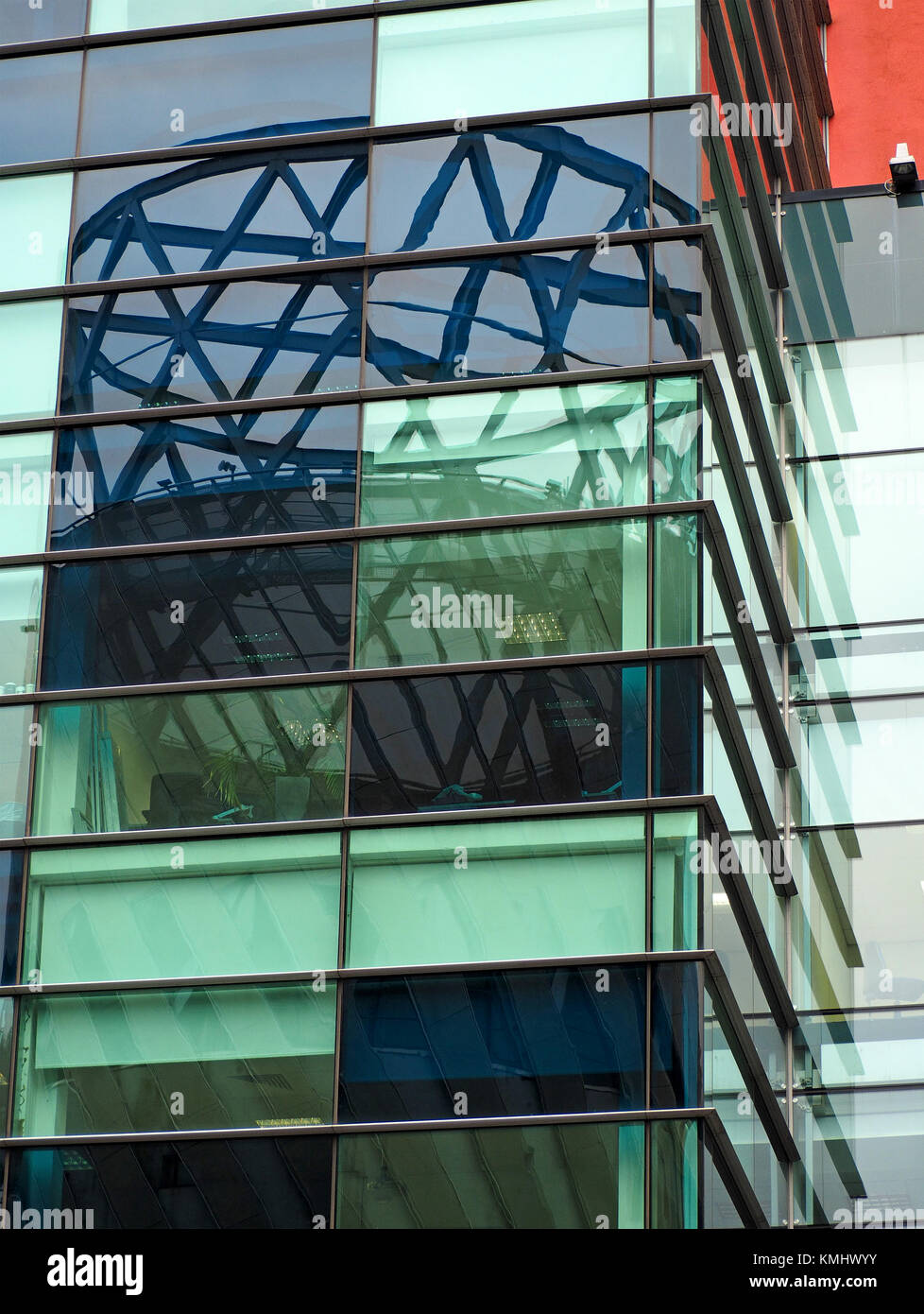 distorted reflections of metallic tower in glazed facade of modern high ...