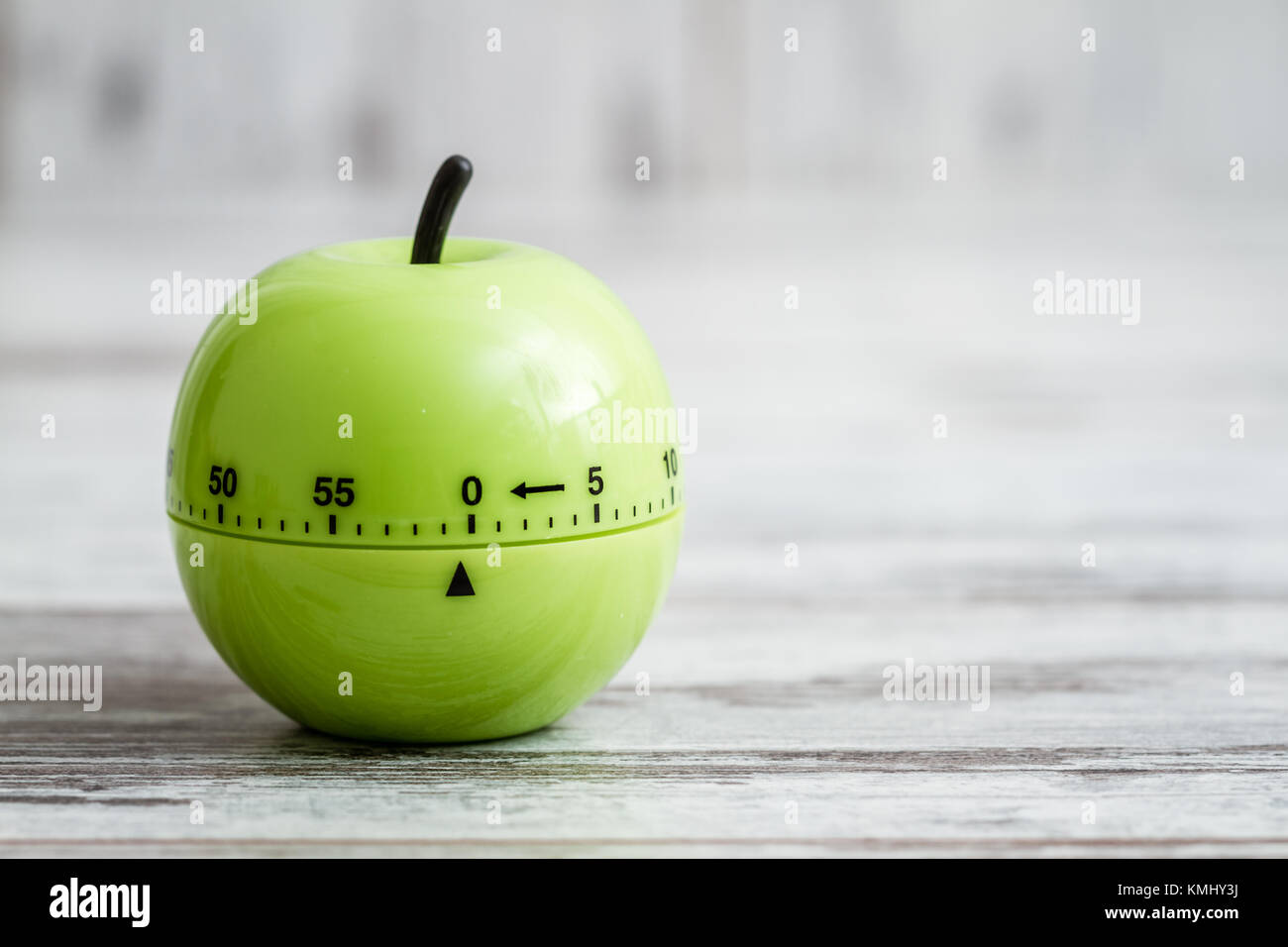 Green kitchen cooking timer with apple shape on white wooden background ...