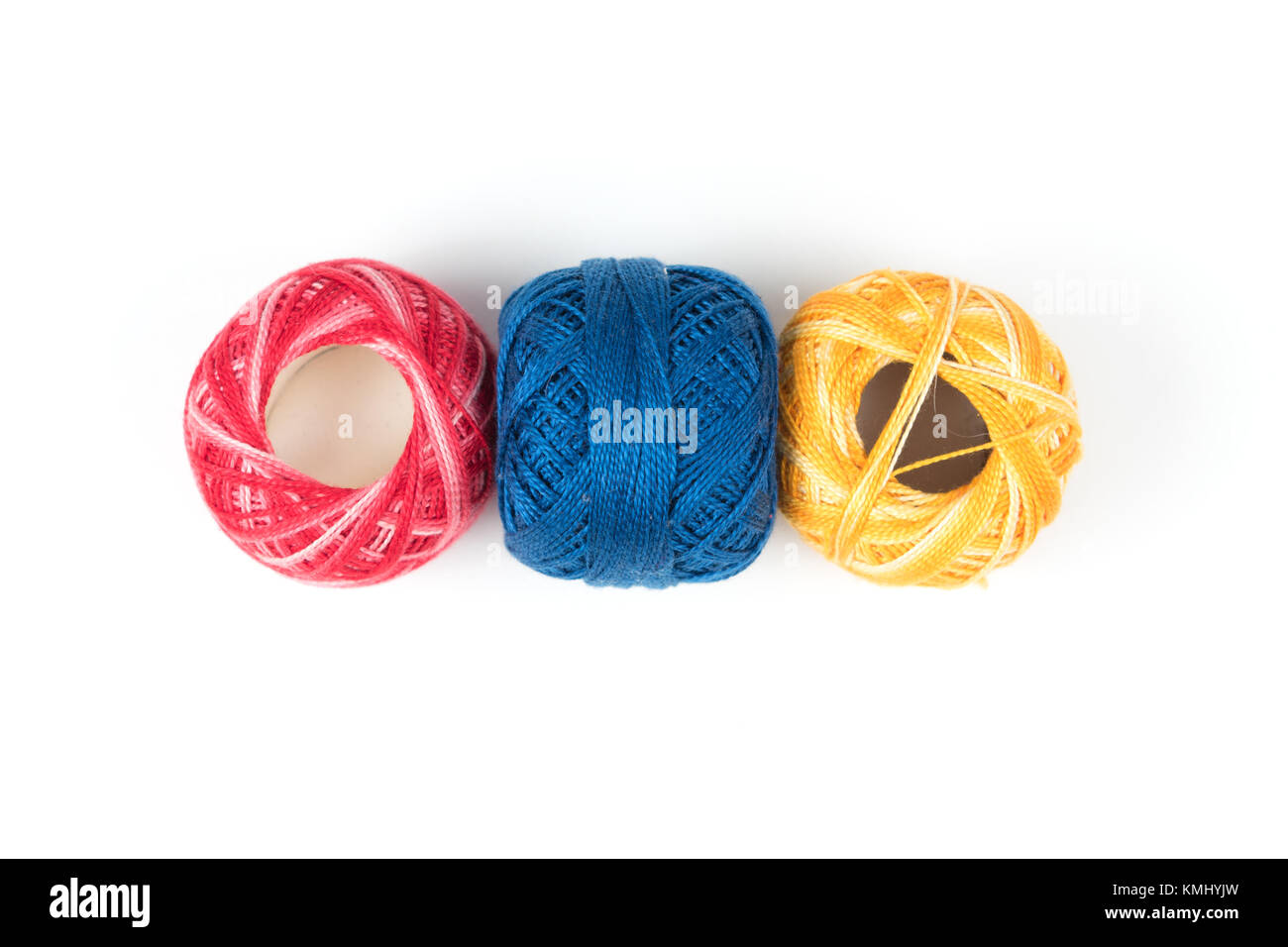 Three colored sewing threads on a white background, yellow, blue and ...