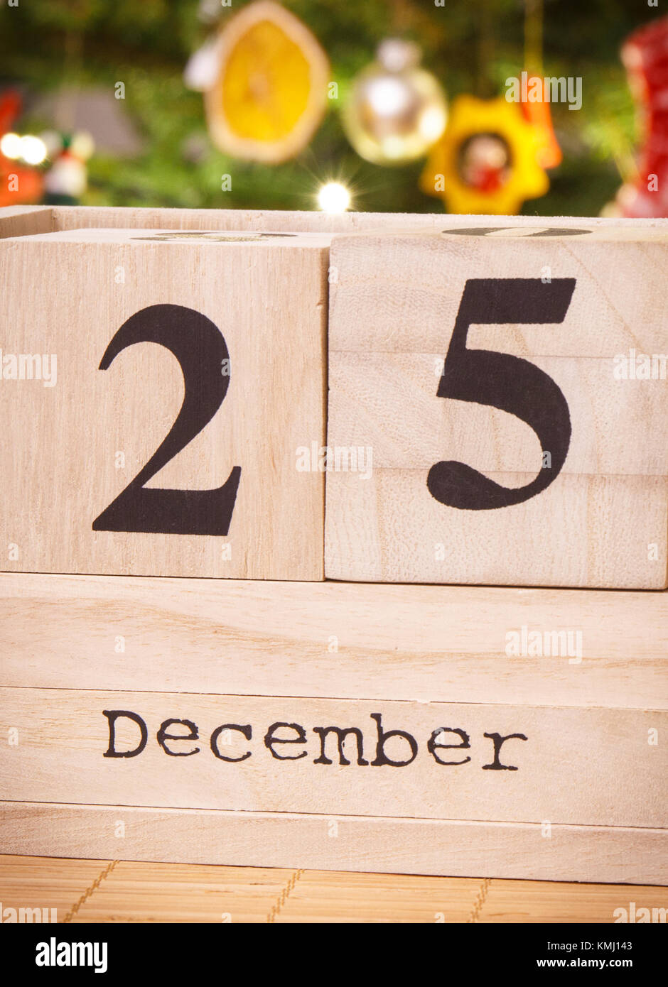 Date 25 December on cube calendar, festive tree with lights and ...