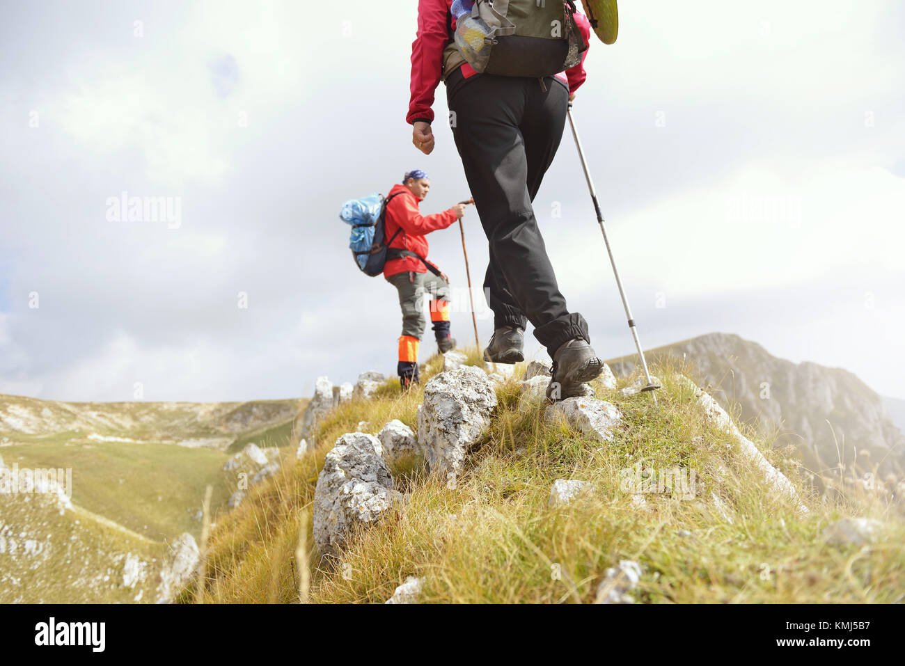 Close-up of legs of young hikers walking on the country path. Young ...