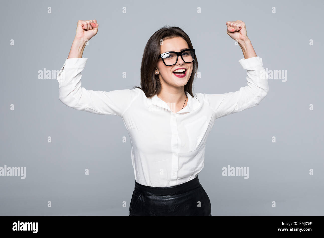 Portrait of a beautiful young woman keeping her arms raised standing ...