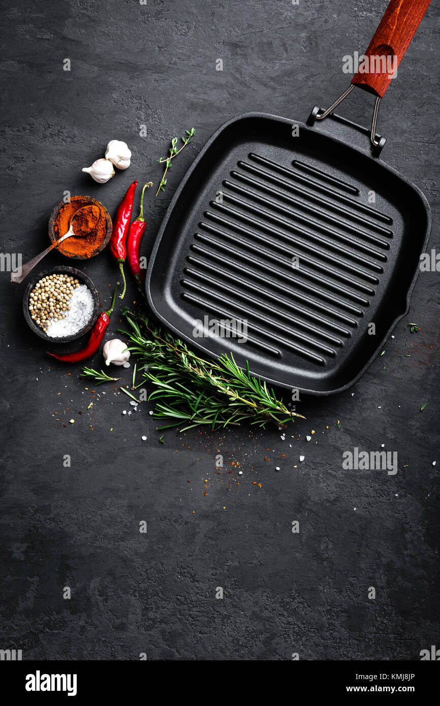 Empty cast-iron grill pan with ingredients for cooking on black ...