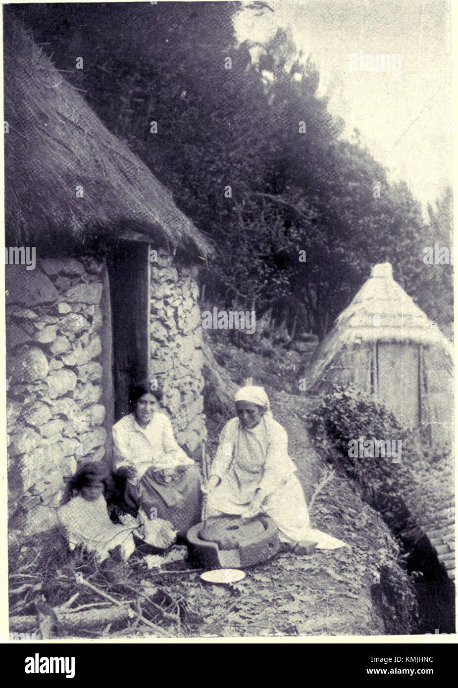 A historical photograph from 1909 showing peasants grinding maize. The ...