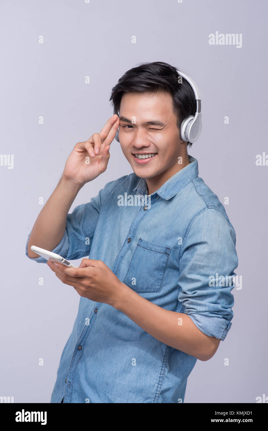 Handsome young man wearing headphones and holding mobile phone while ...