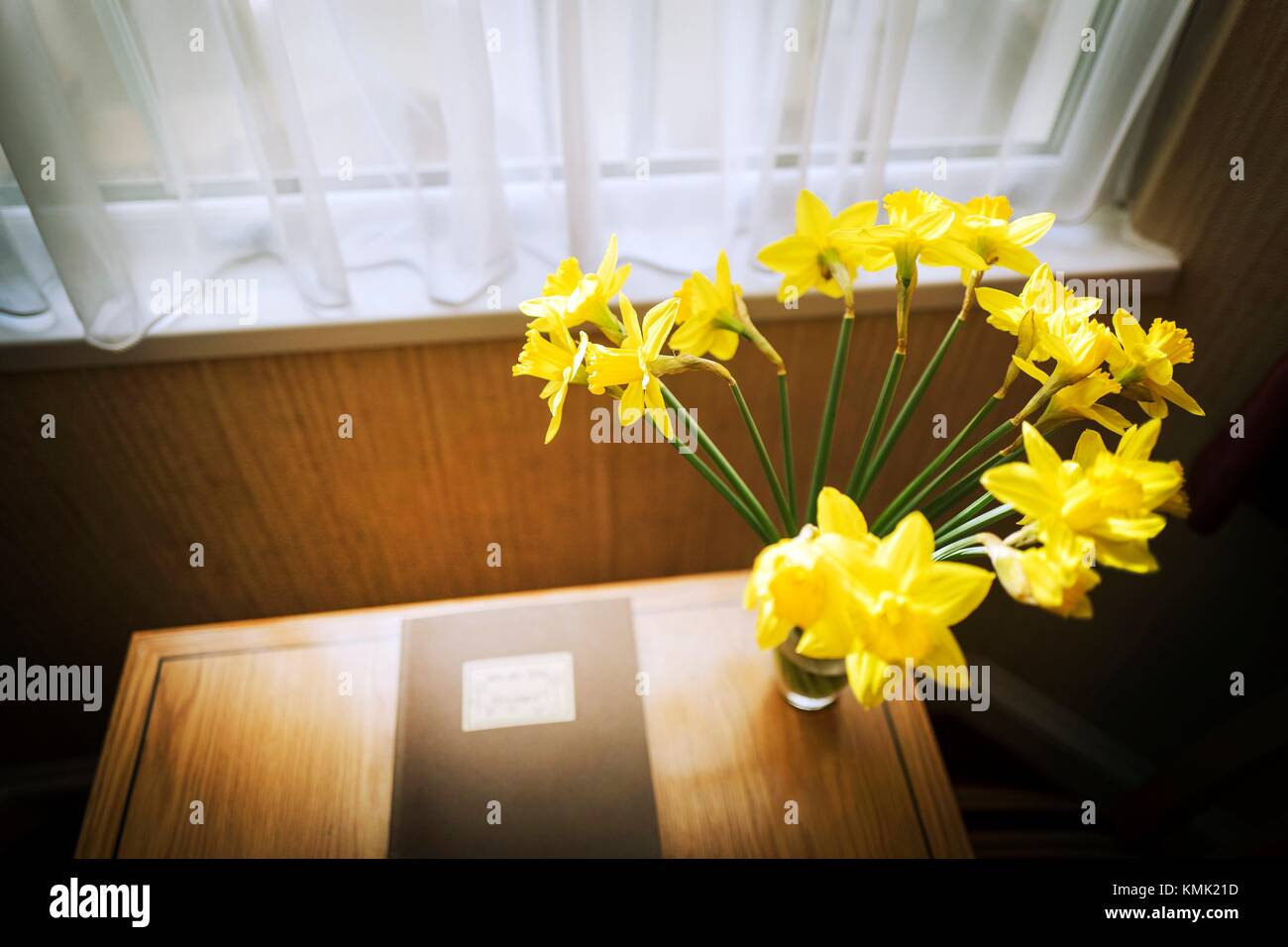 Table beside window with book and vase with yellow flowers inside house ...