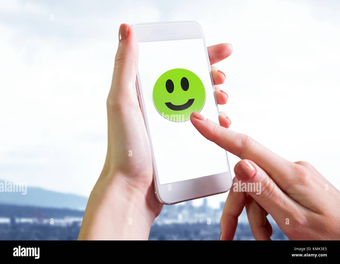 Digital composite of Hand touching smiley face on phone Stock Photo - Alamy